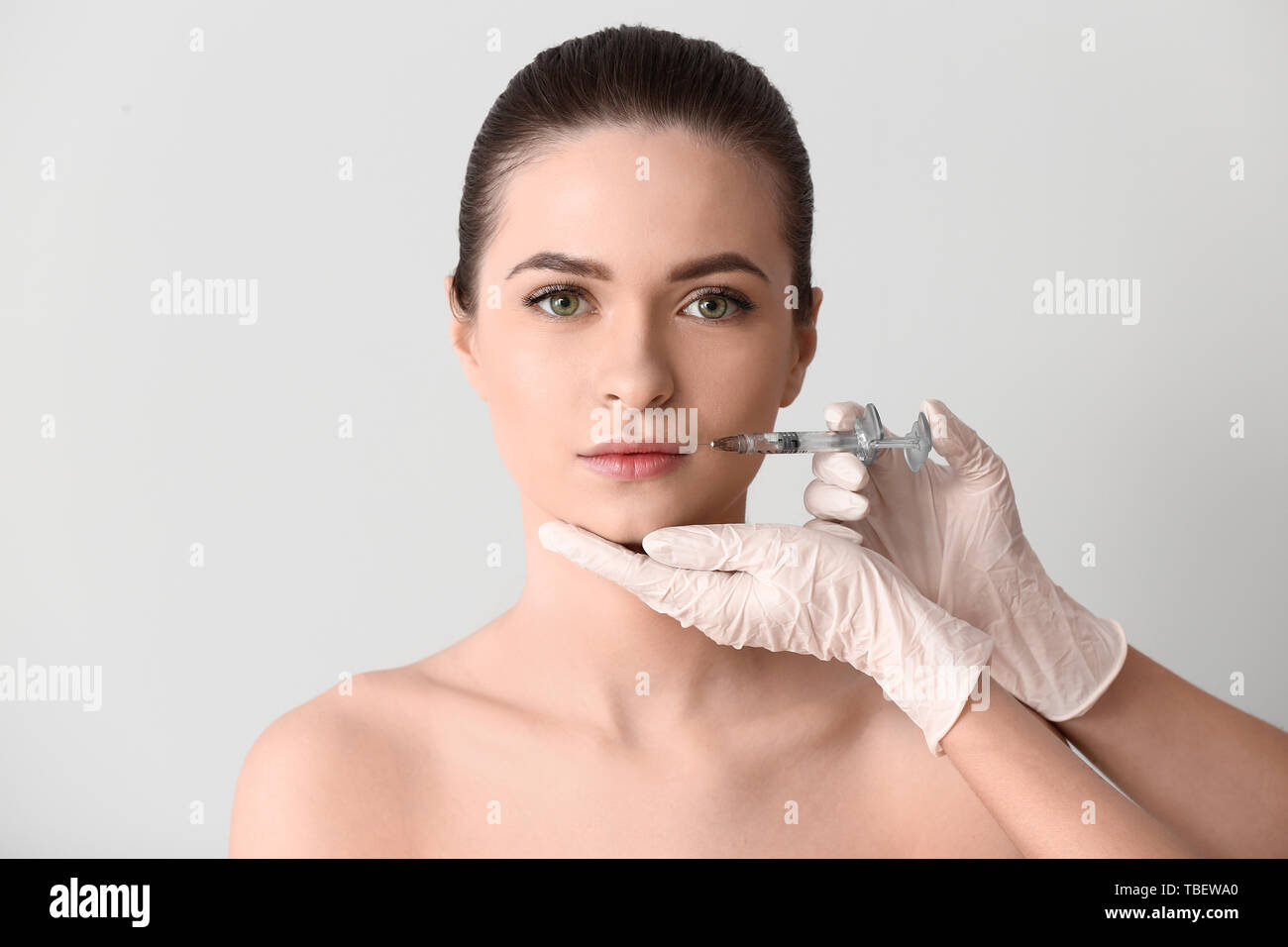 Young woman receiving injection in face on light background Stock Photo ...