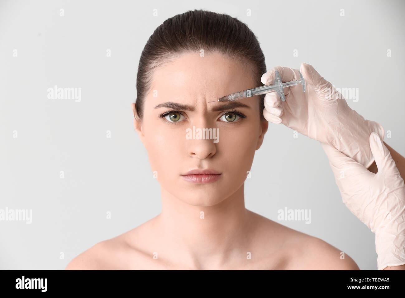 Young woman receiving injection in face on light background Stock Photo ...
