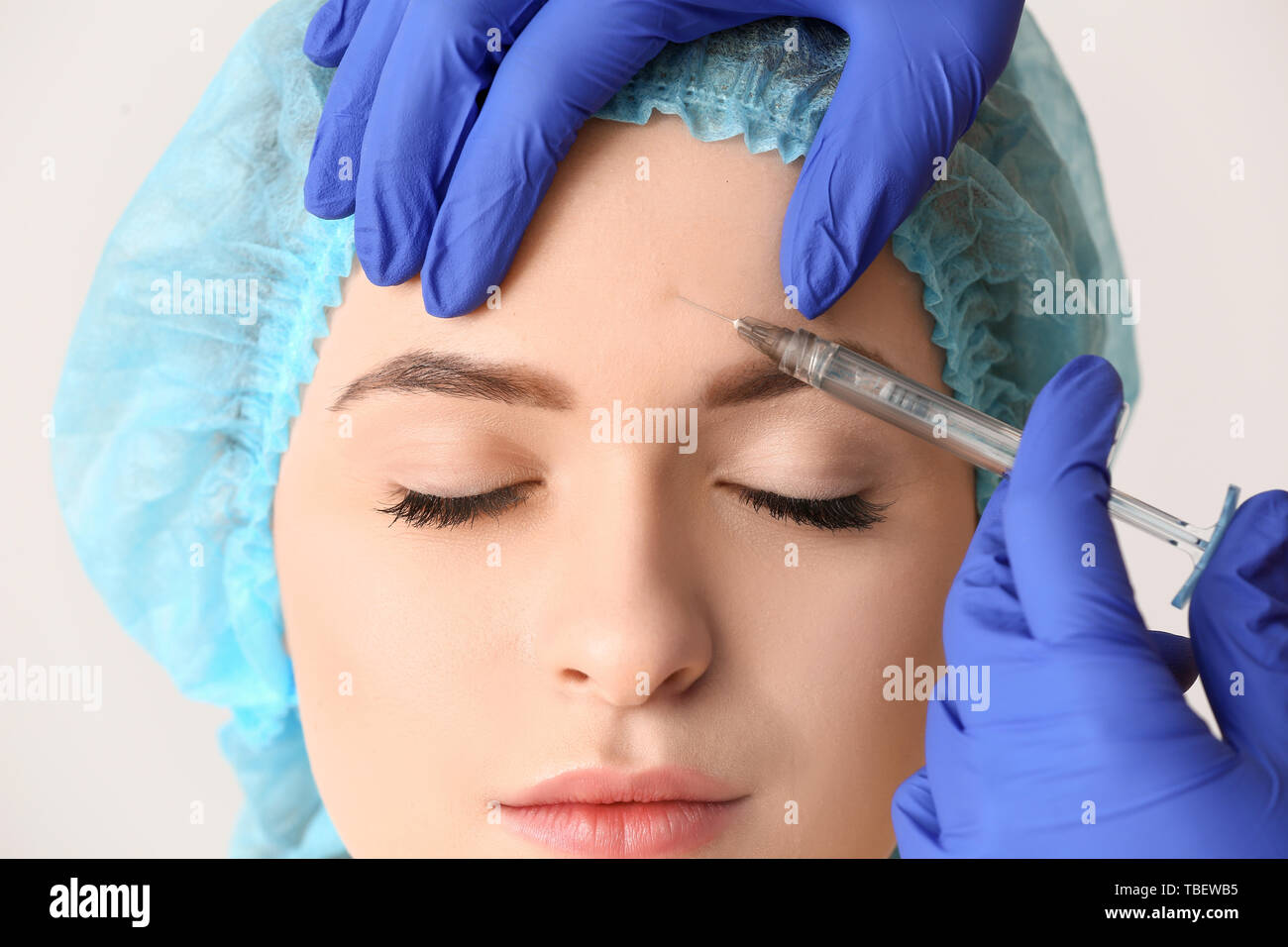 Young woman receiving injection in face on light background, closeup ...