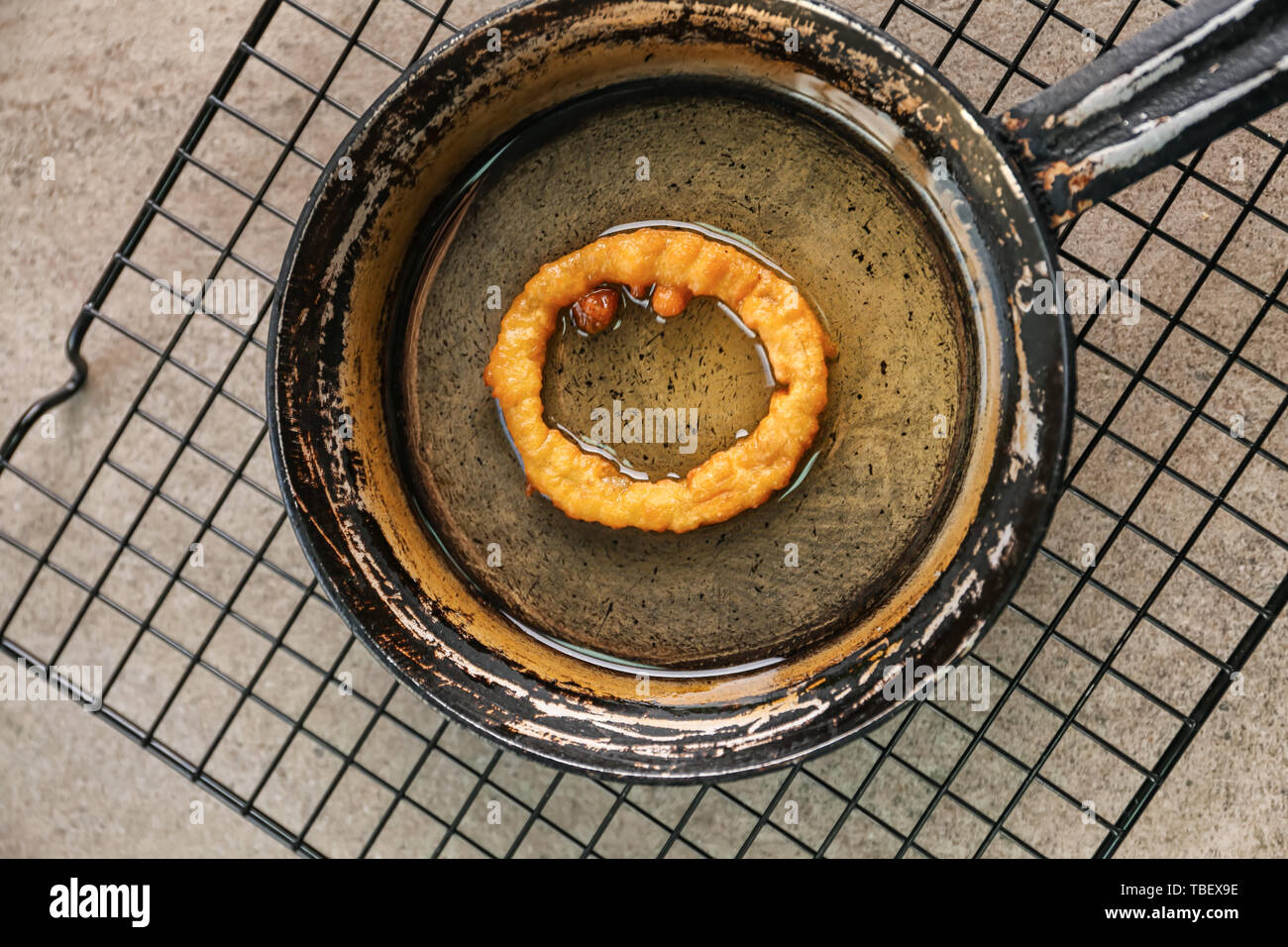 Frying pan with tasty onion ring on cooling rack Stock Photo - Alamy