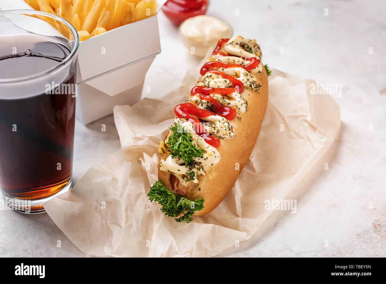 Tasty hot dog with drink on light table Stock Photo - Alamy