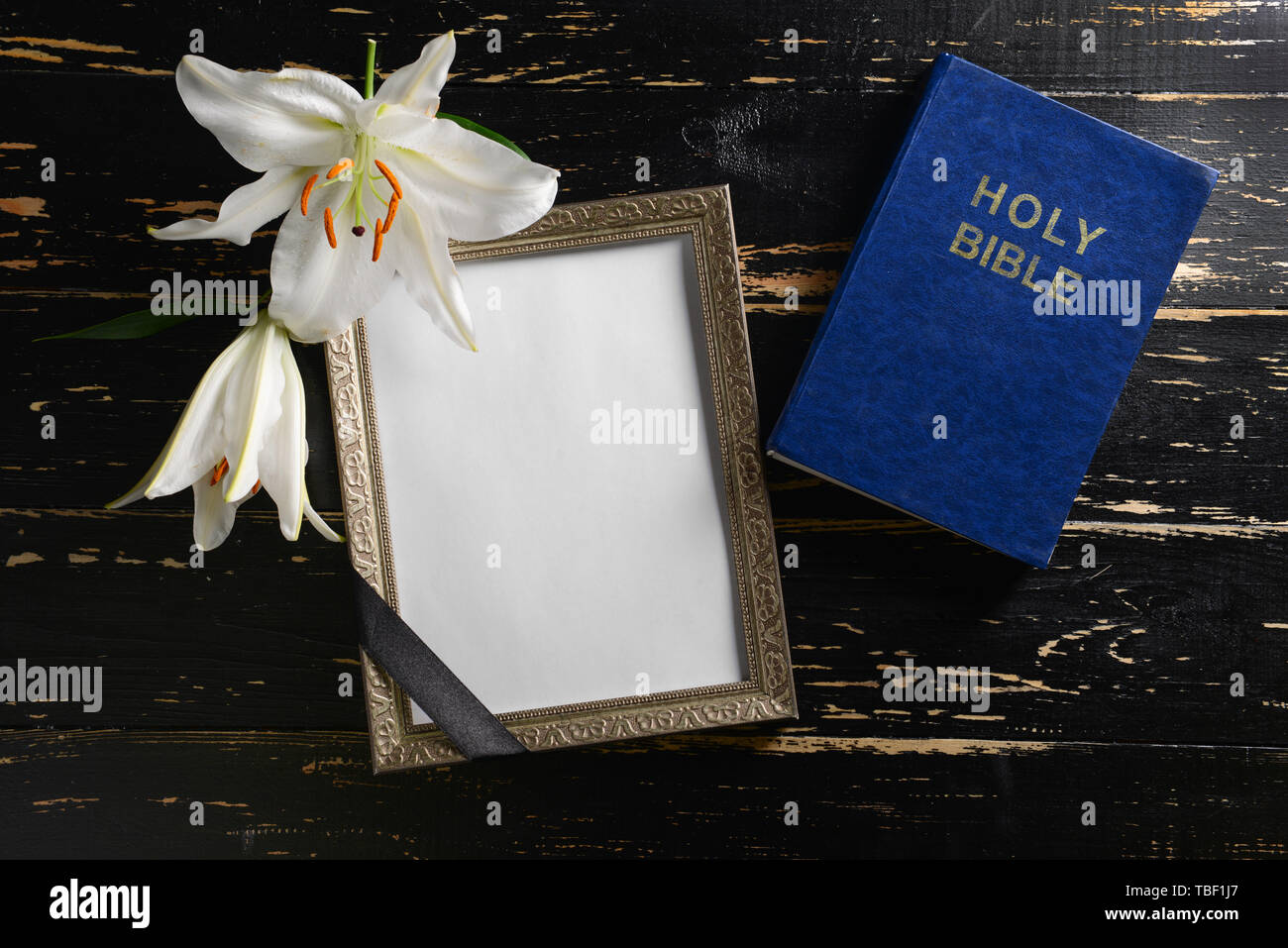 Blank funeral frame, flowers and Bible on dark wooden background Stock ...