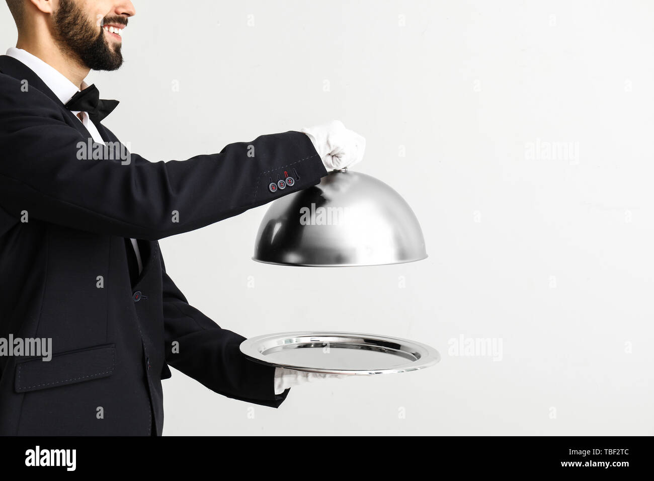 Waiter with tray and cloche on light background Stock Photo - Alamy