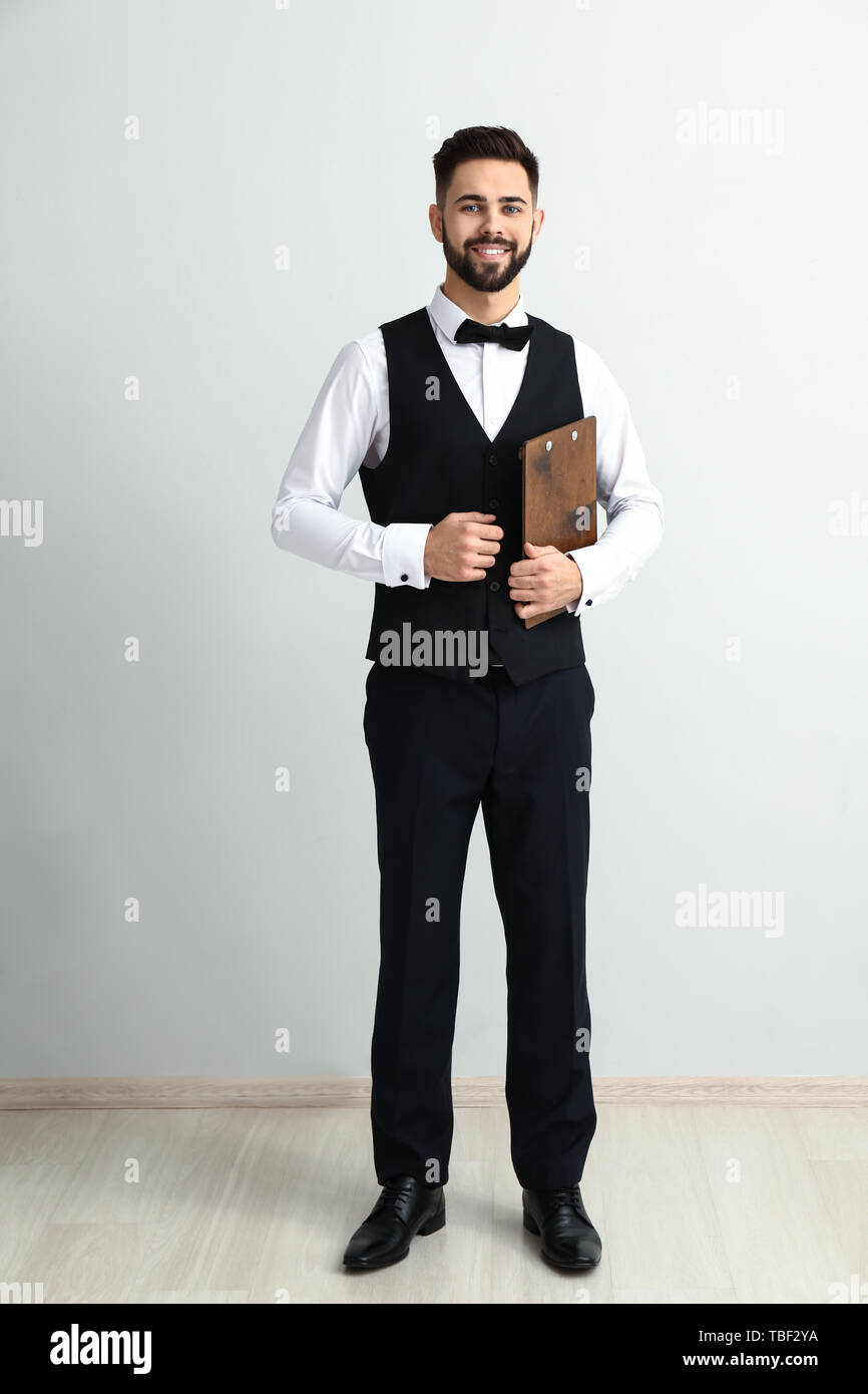 Waiter with menu near light wall Stock Photo - Alamy