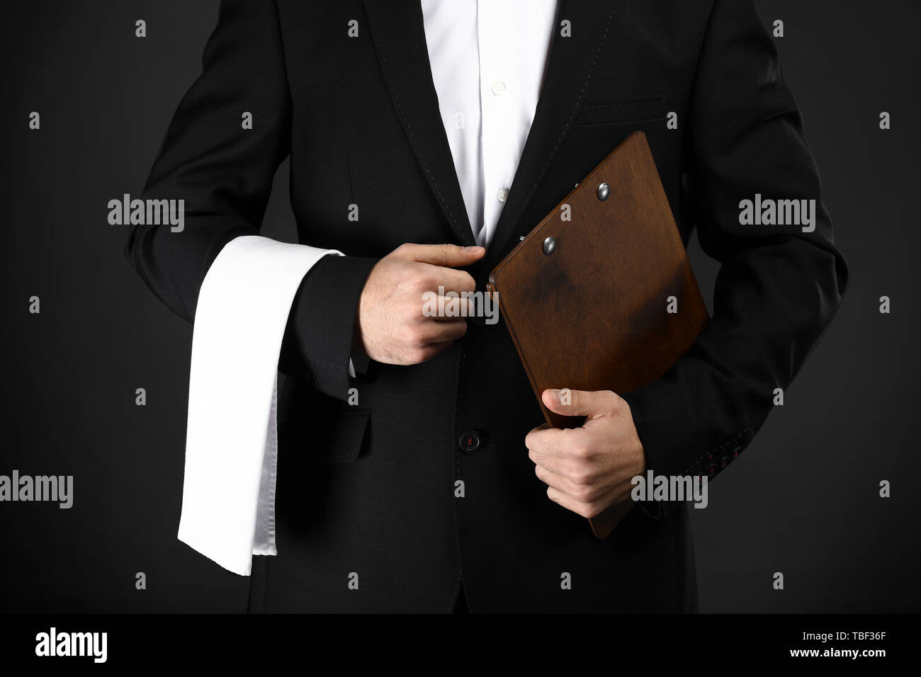 Handsome waiter with menu on dark background Stock Photo - Alamy
