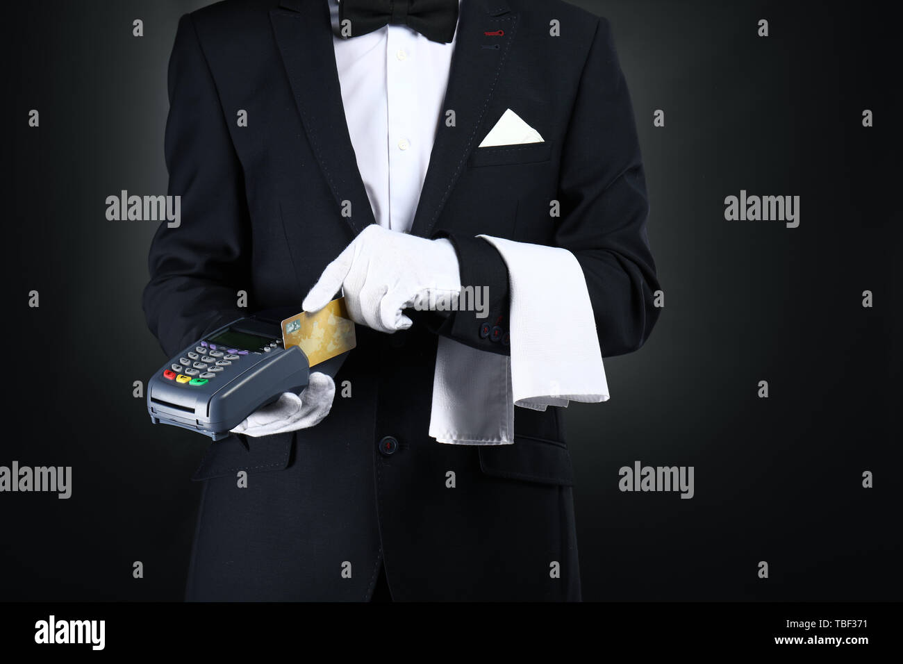Handsome waiter with payment terminal on dark background Stock Photo ...