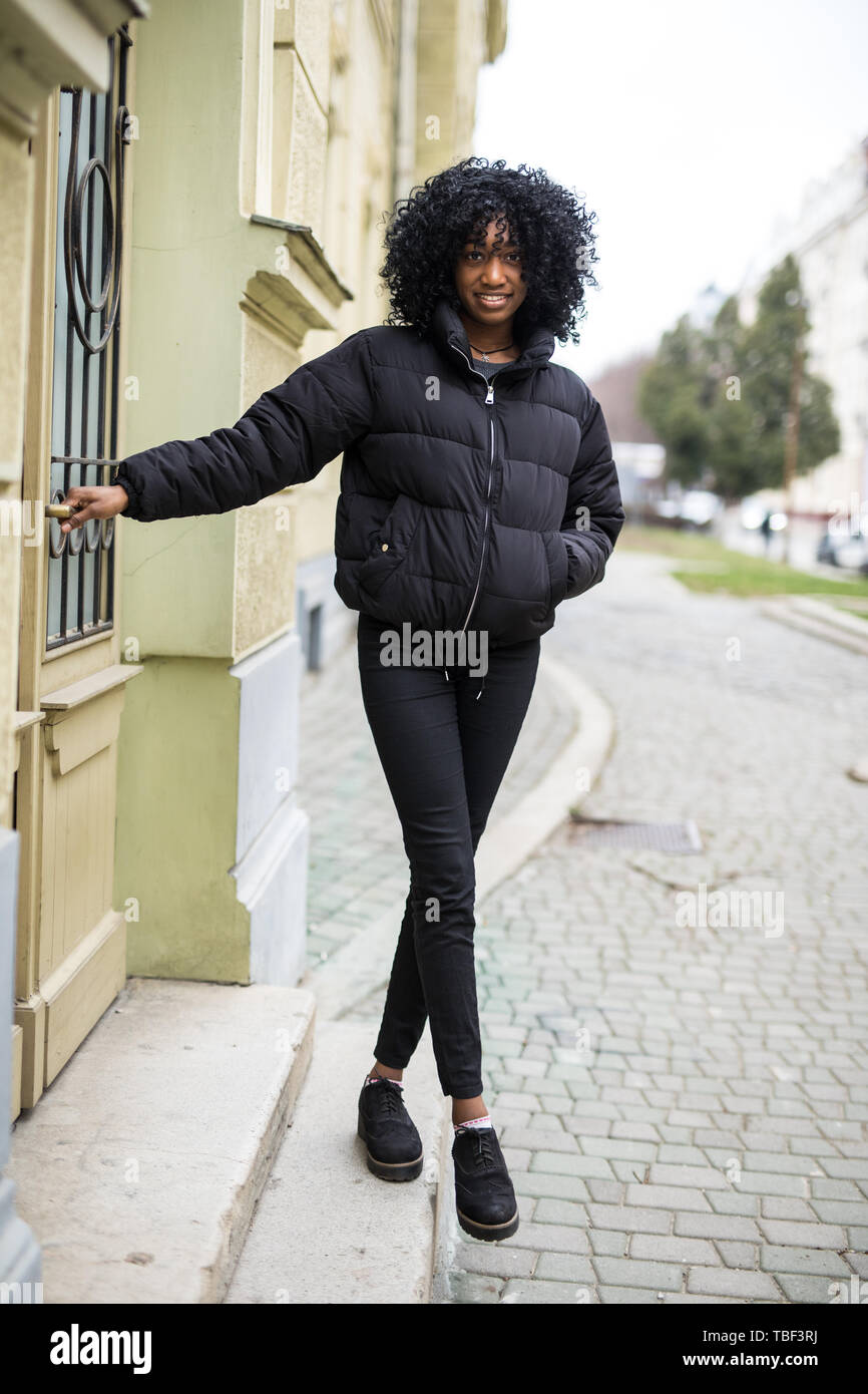 Cheerful young african woman wearing coat walking outdoors Stock Photo - Alamy