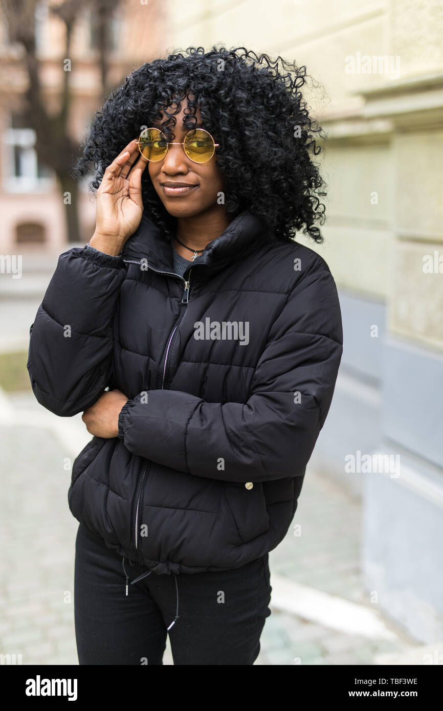Cheerful young african woman wearing coat walking outdoors Stock Photo - Alamy