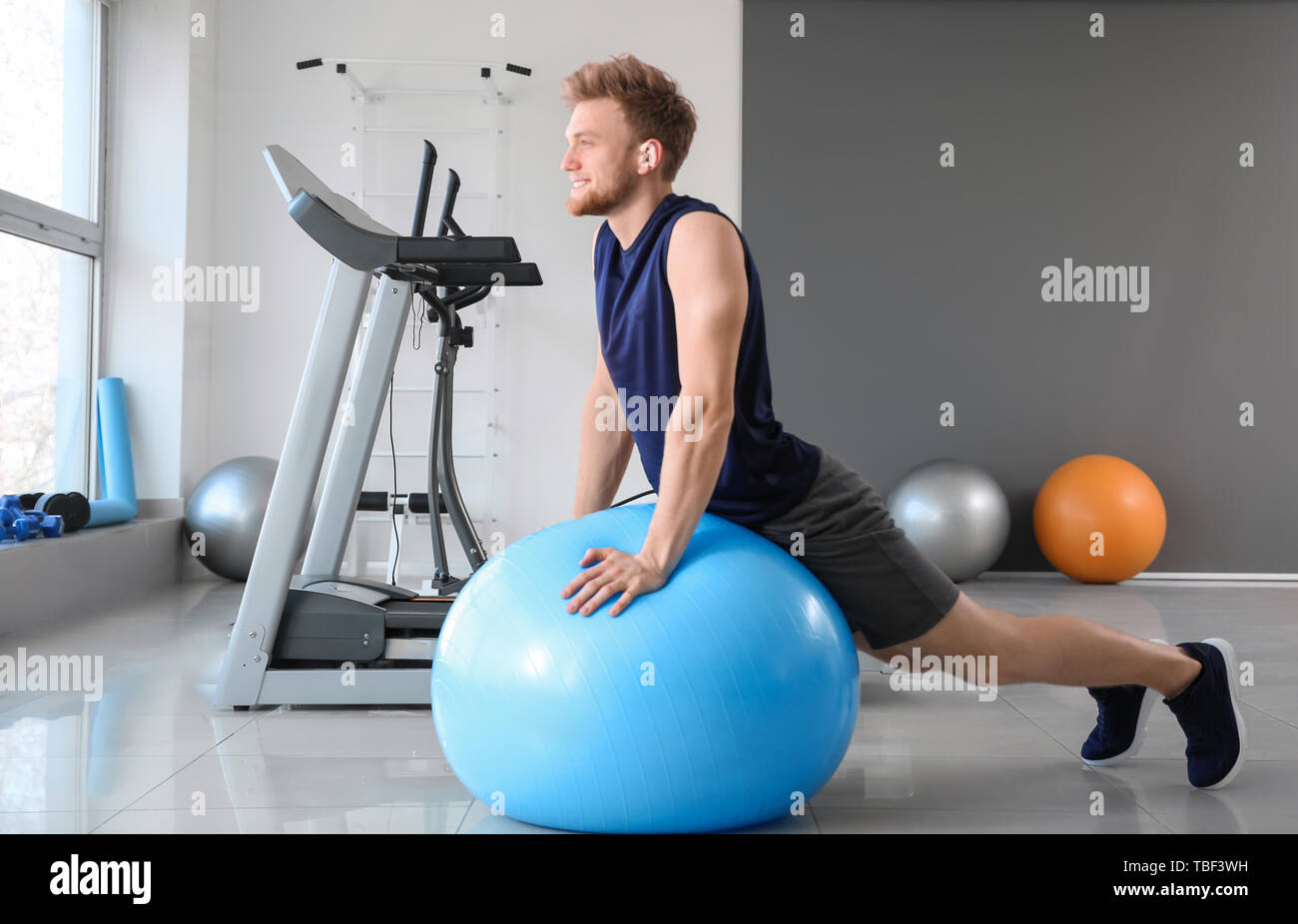 Sporty young man training with fitball in gym Stock Photo - Alamy