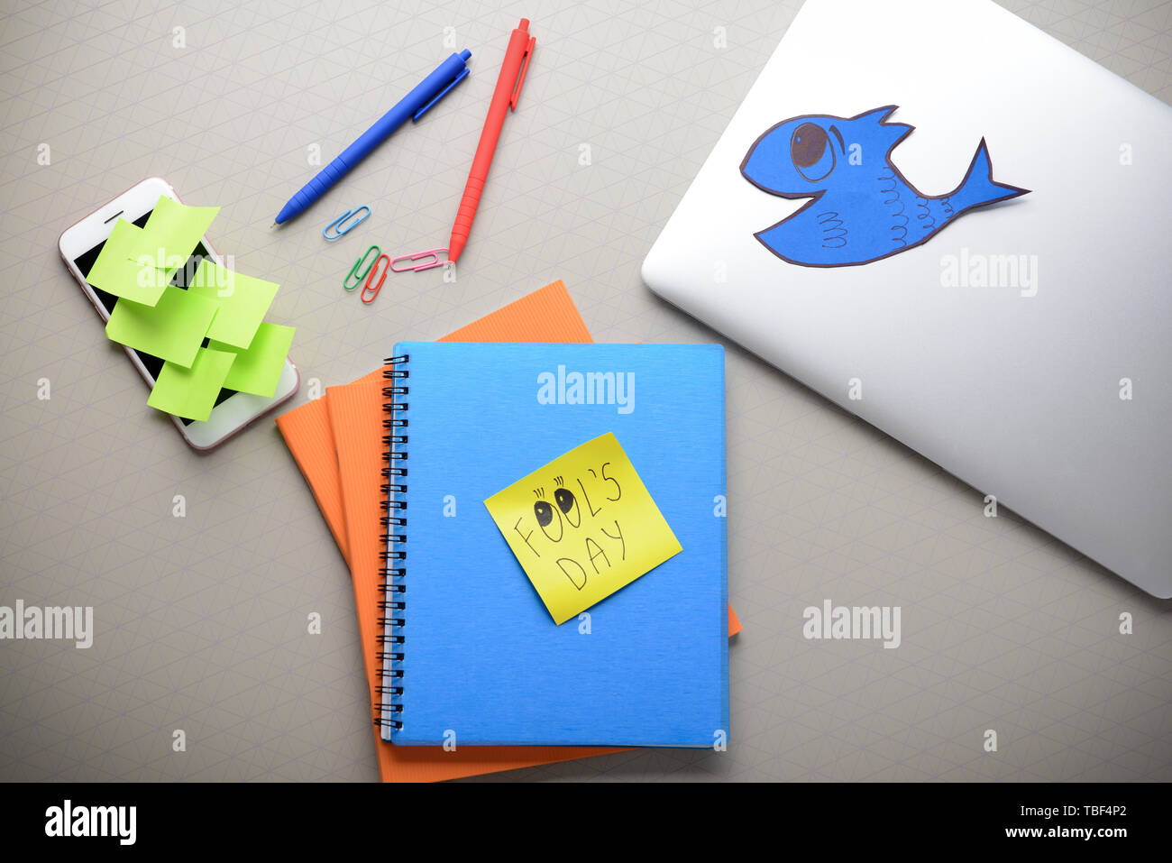 Devices with stationery, paper fish and sticky note with text FOOL'S ...