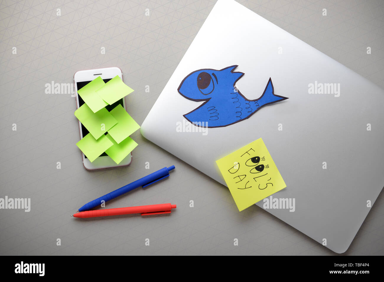 Devices with stationery, paper fish and sticky note with text FOOL'S ...
