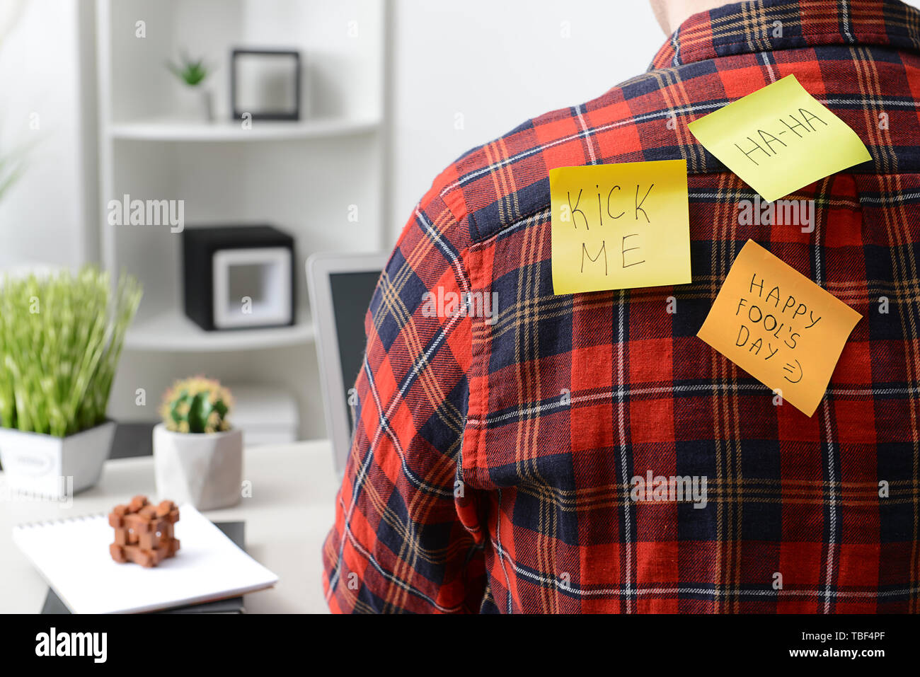 Sticky notes on back of young man working in office. April Fool's Day ...
