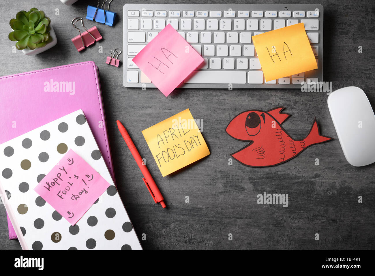 Computer keyboard with stationery, paper fish and sticky notes on grey ...
