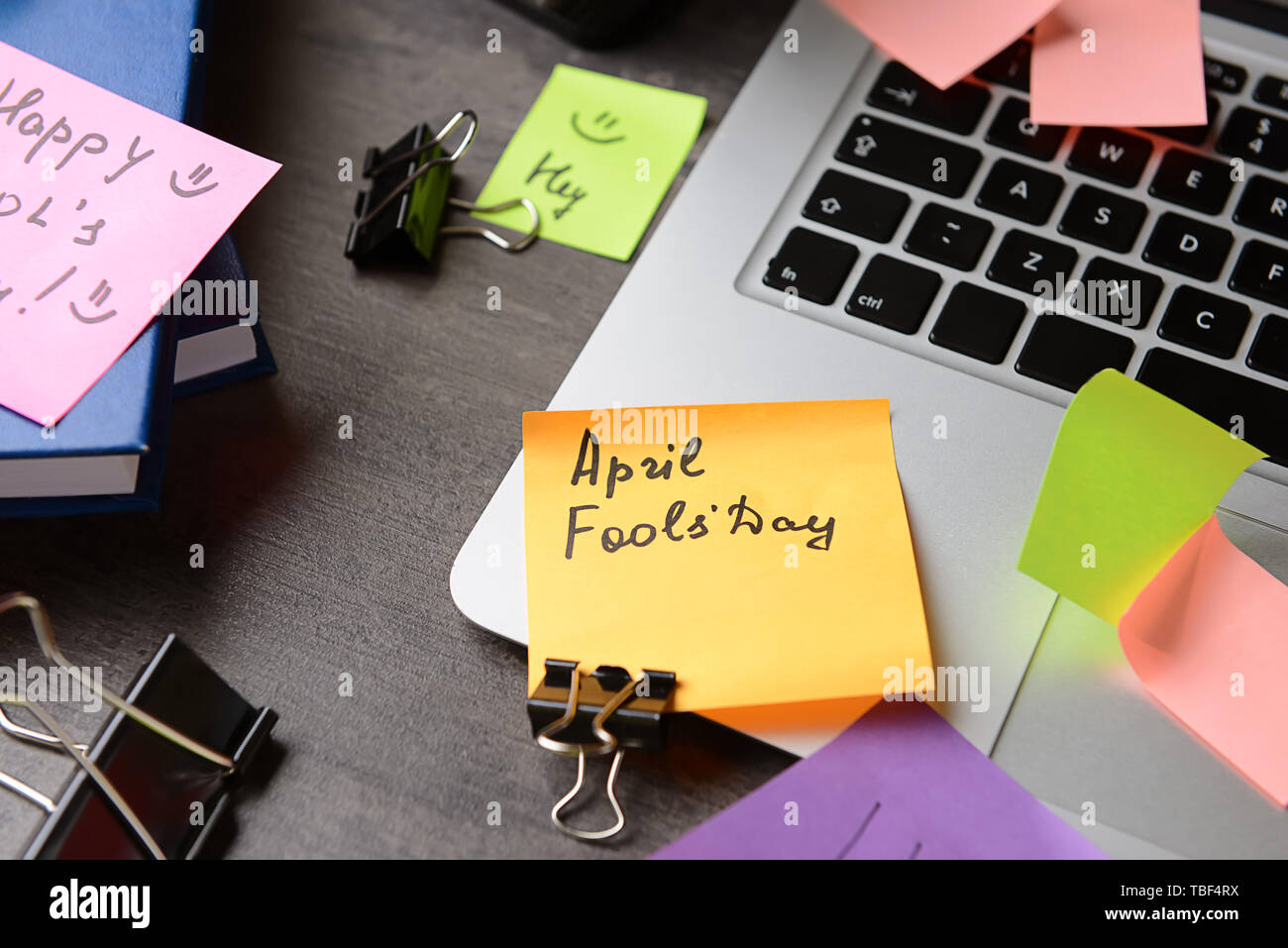 Laptop with stationery and sticky notes on grey background. April Fool ...