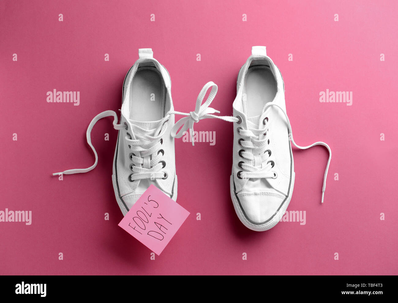 Shoes with tied laces and sticky note with text FOOL'S DAY on color ...