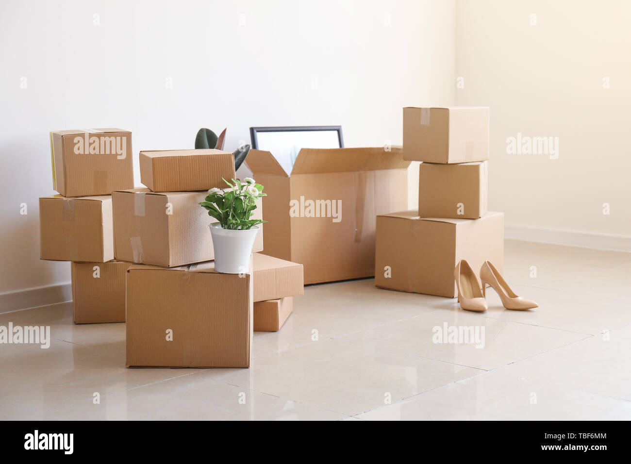 Moving boxes with belongings in empty room Stock Photo - Alamy