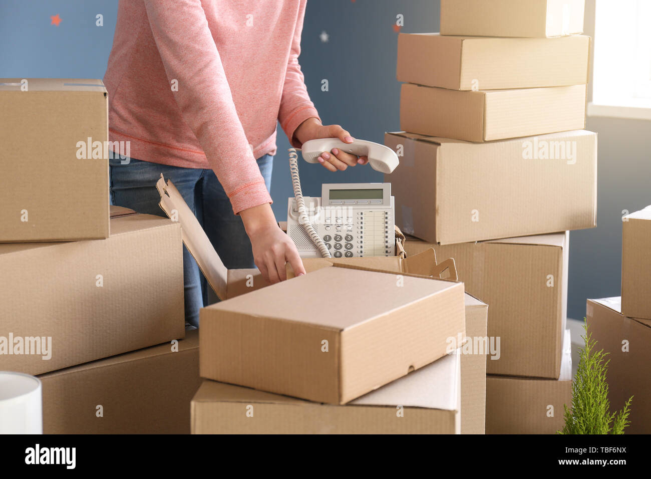 Young woman packing telephone into box Stock Photo - Alamy