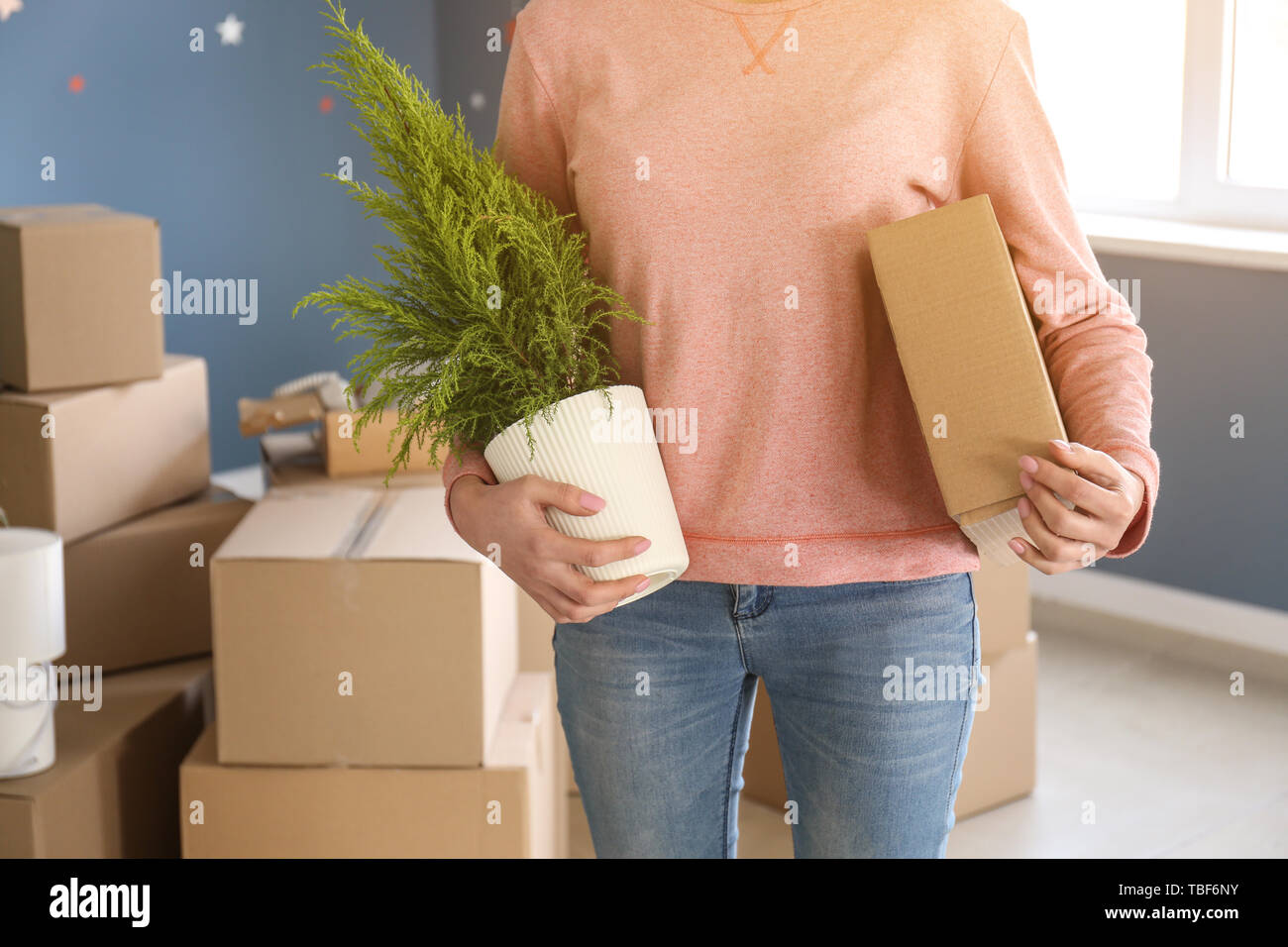 Woman with moving box and plant in room Stock Photo - Alamy