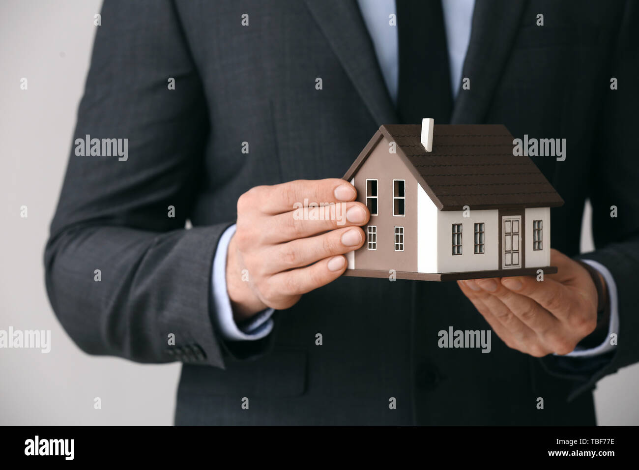Insurance agent with model of house, closeup. Protection of house from ...
