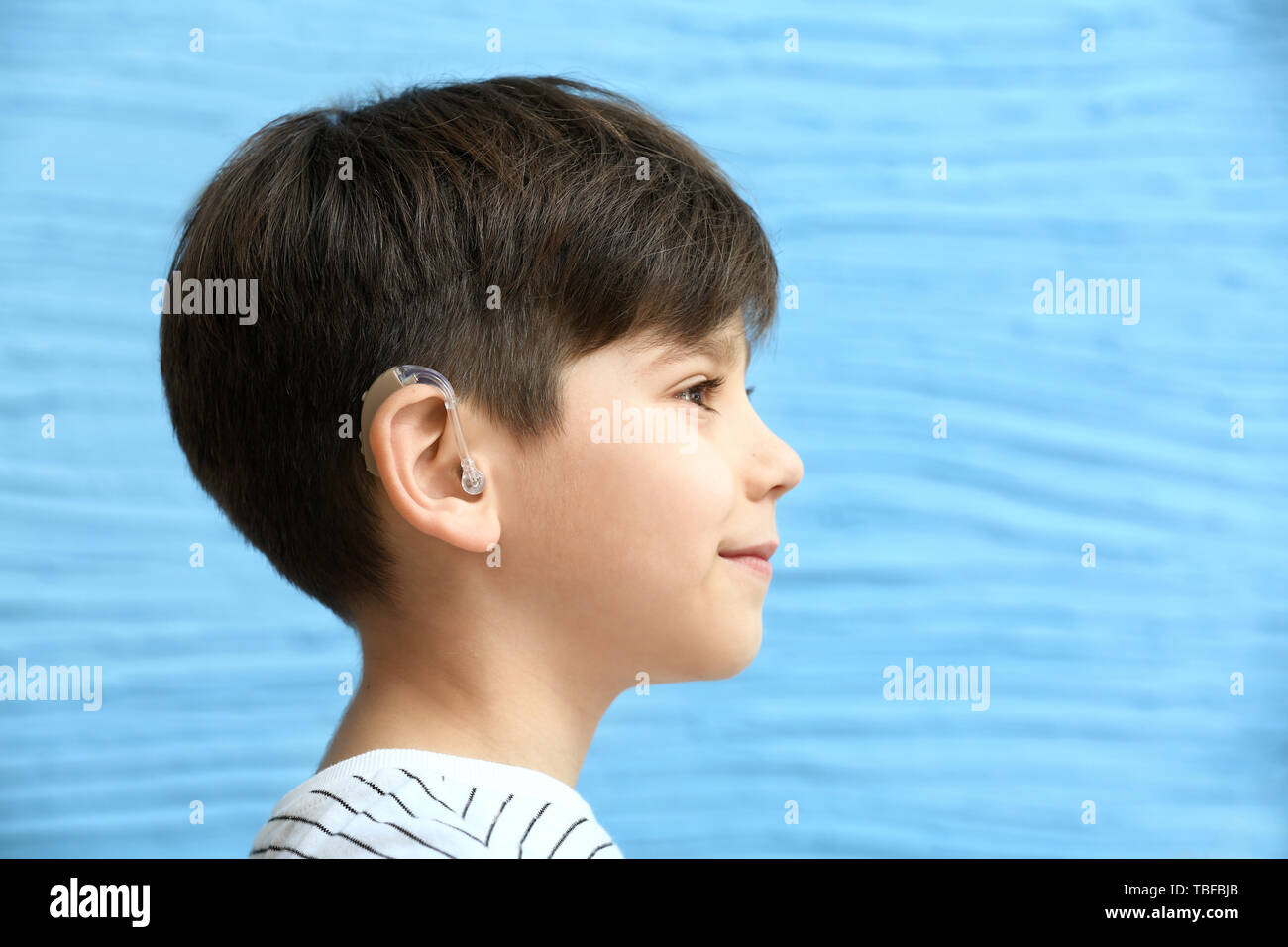Little boy with hearing aid on color background Stock Photo - Alamy