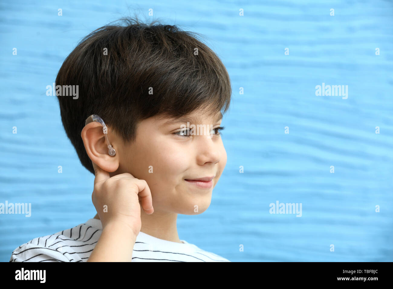Little boy with hearing aid on color background Stock Photo - Alamy