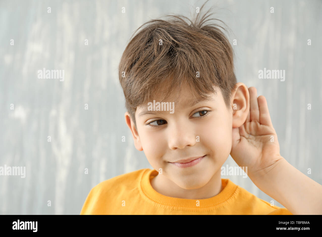 Little boy with hearing problem on grey background Stock Photo - Alamy
