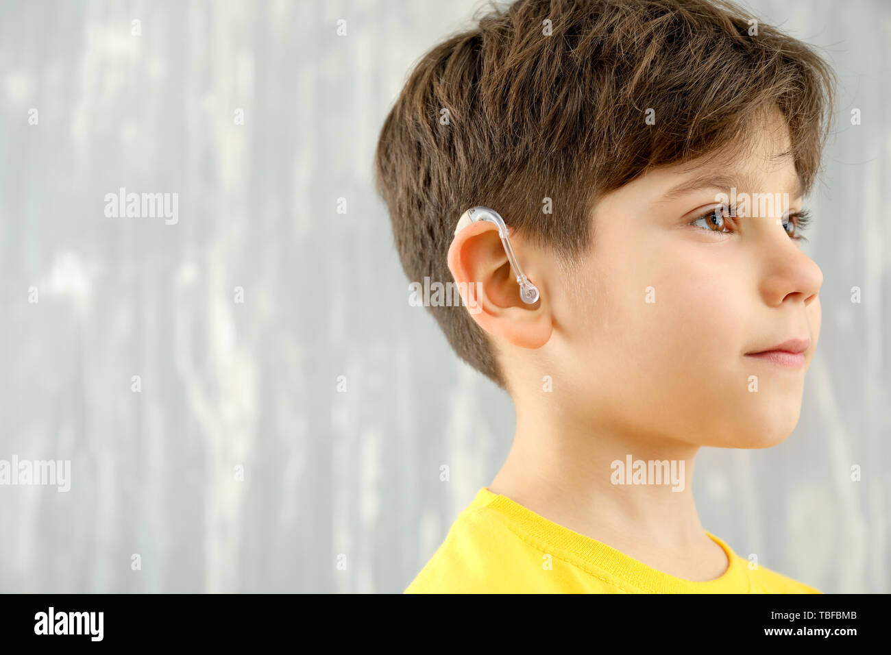 Little boy with hearing aid on grey background Stock Photo - Alamy