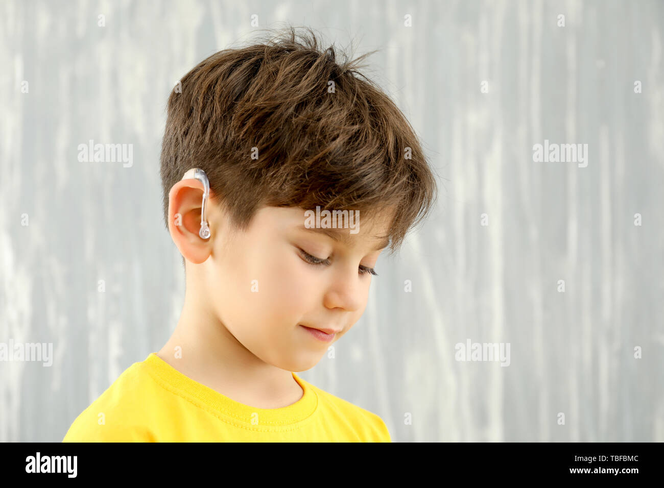 Little boy with hearing aid on grey background Stock Photo - Alamy