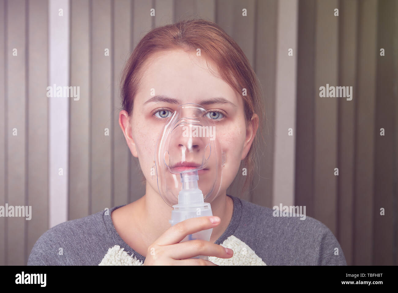 Young woman is breathing with help of nebulizer mask, because she has ...