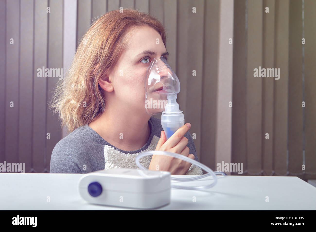 Young woman is breathing with compressor nebuliser system, which uses ...