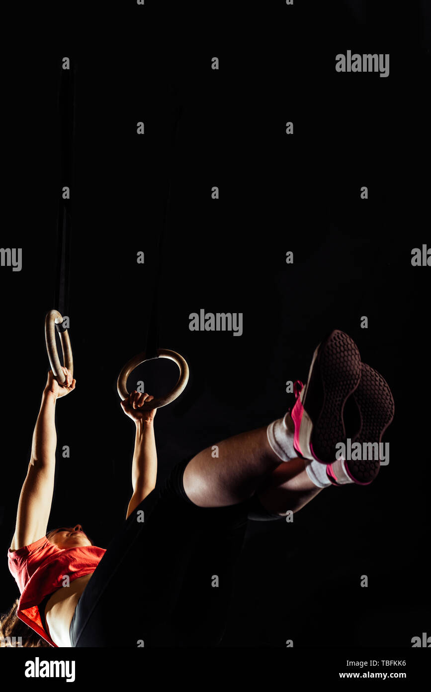 Strong young woman doing pull-ups exercise using gymnastic rings at gym ...