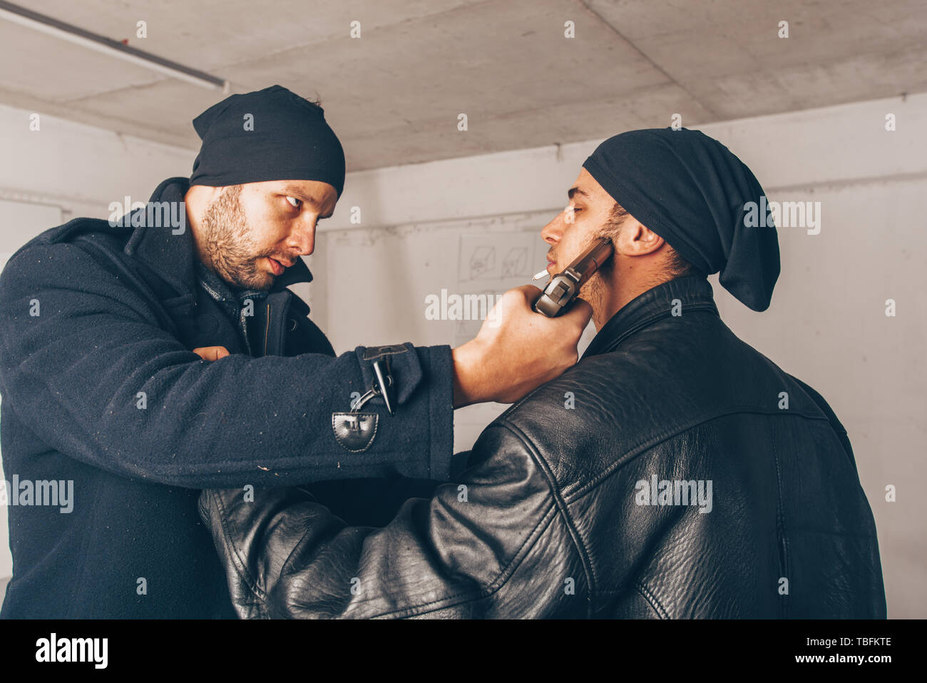 Two criminals are in a smoky room, one of them is pointing a gun at his ...