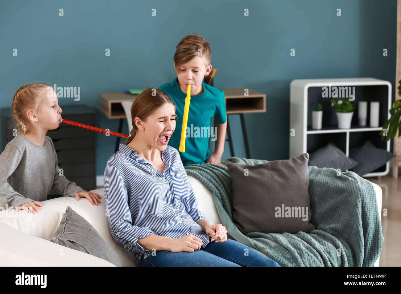 Little children with party whistles frightening mother at home. April ...