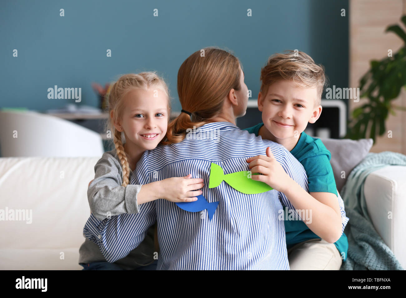 Little children sticking paper fish to their mother's back. April fools ...