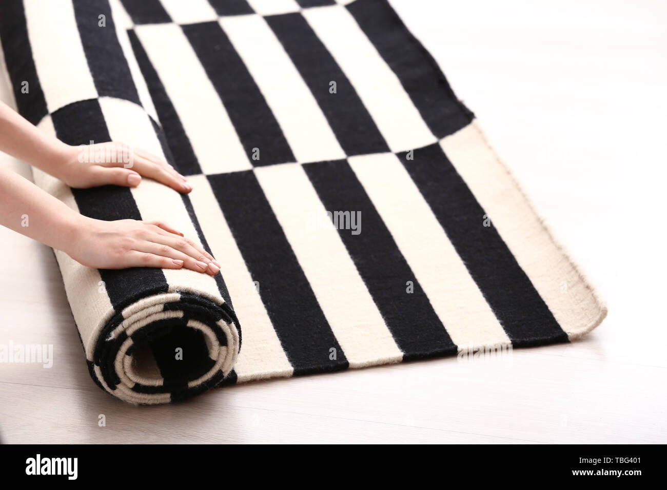 Woman rolling carpet on floor in room Stock Photo - Alamy