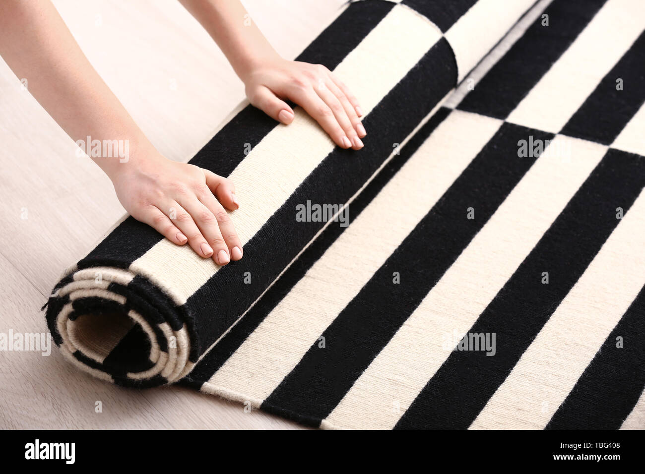 Woman rolling carpet on floor in room Stock Photo - Alamy