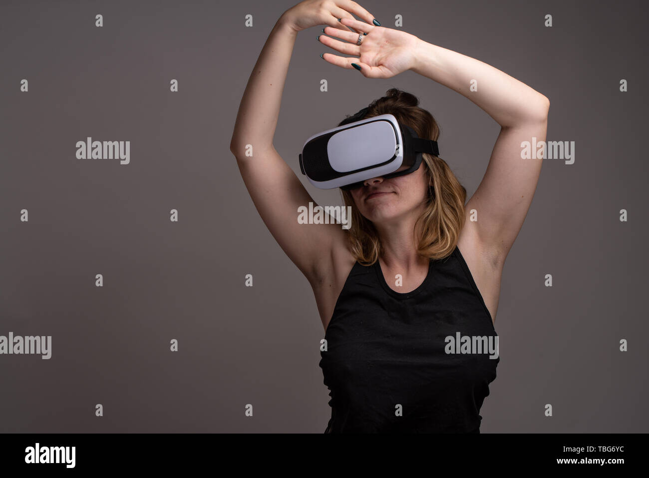 Young female using VR gear is dancing and stretching hands Stock Photo ...
