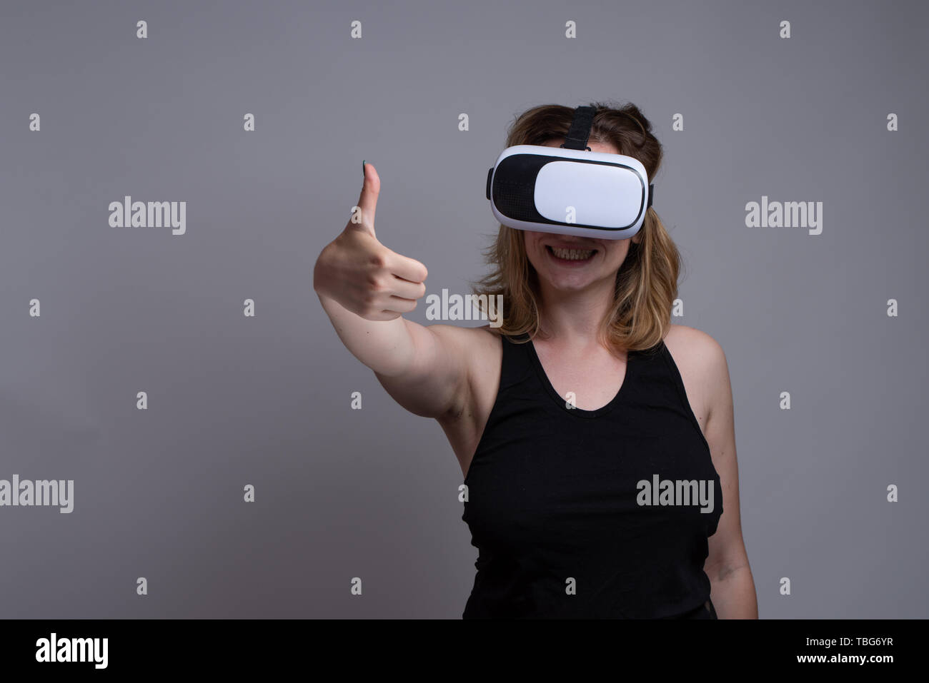 Young female using a 3D VR wearable is displaying a happy face and ...