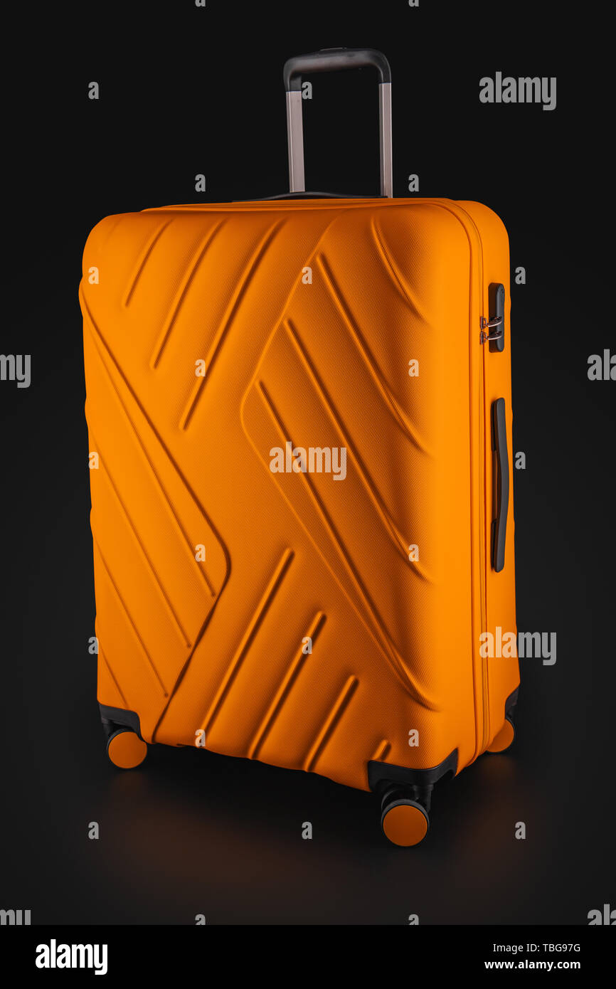 Orange suitcase with luggage for flight isolated on black background ...