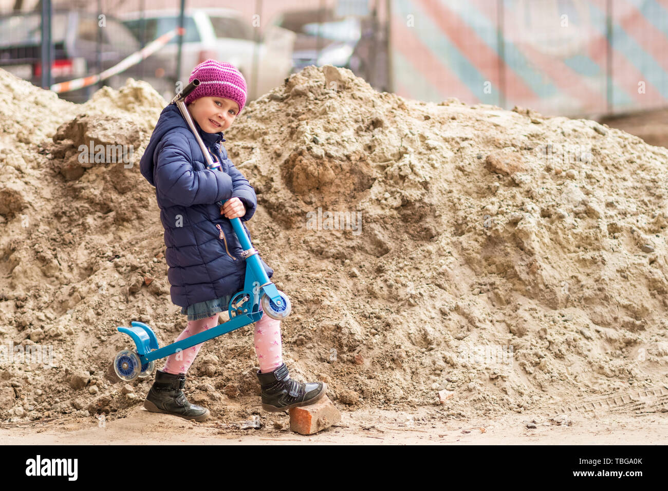 beautiful child carries a scooter on his shoulder, stepping over a ...