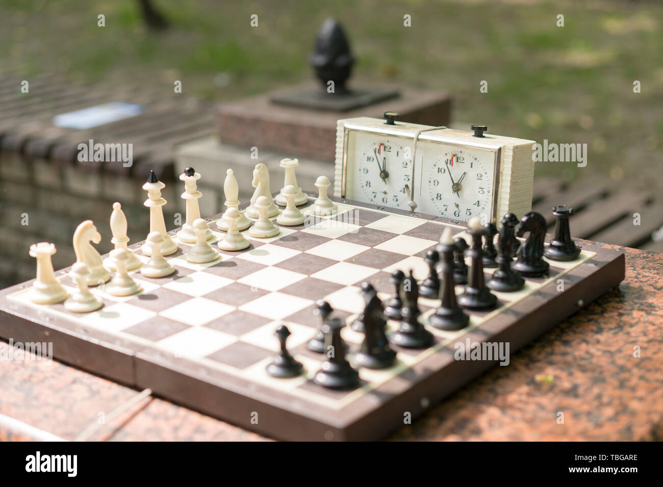 Chess board with pieces and clock on wooden desk In connection with the ...