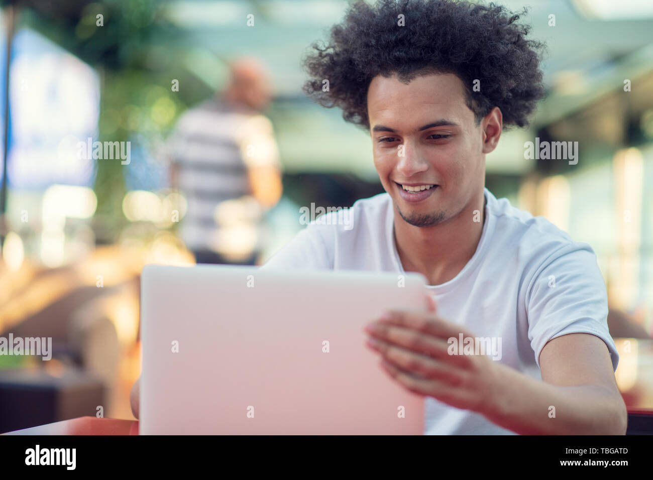 Victorious handsome man looking at his laptop while sitting in bright ...