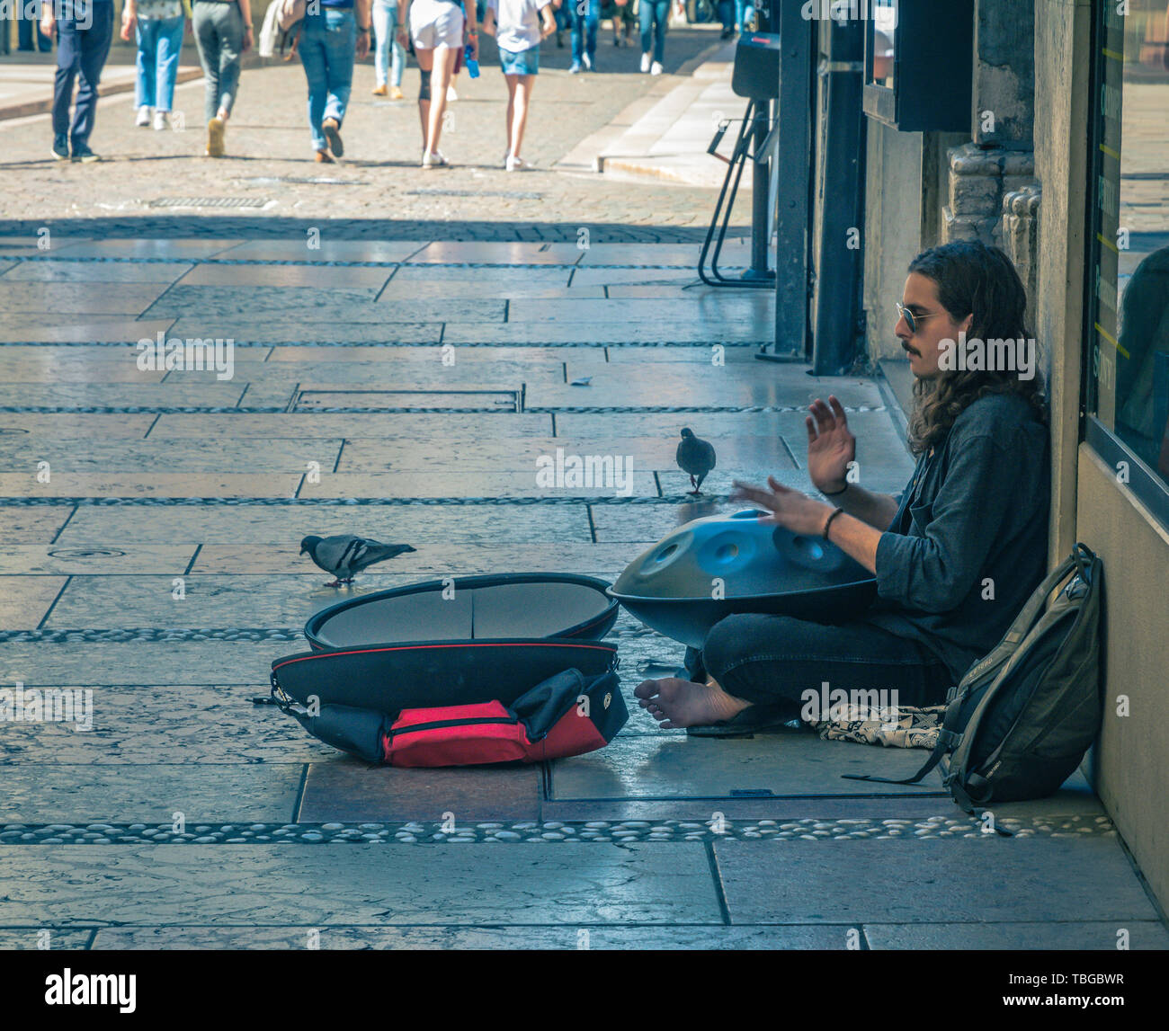young man playing music with Hang - drum hang instruments on the street ...