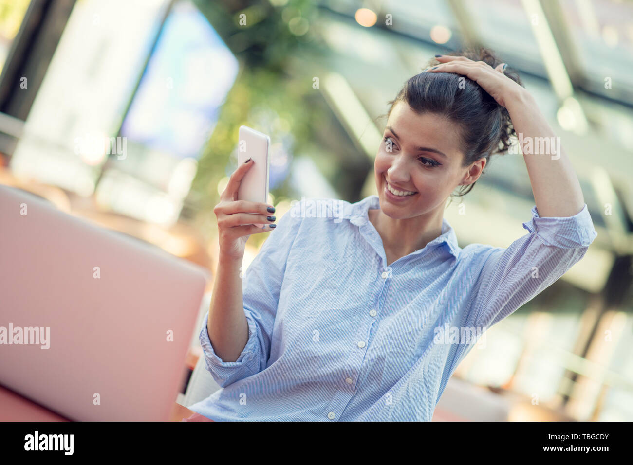 Portrait of a playful young girl taking selfie with mobile phone while ...
