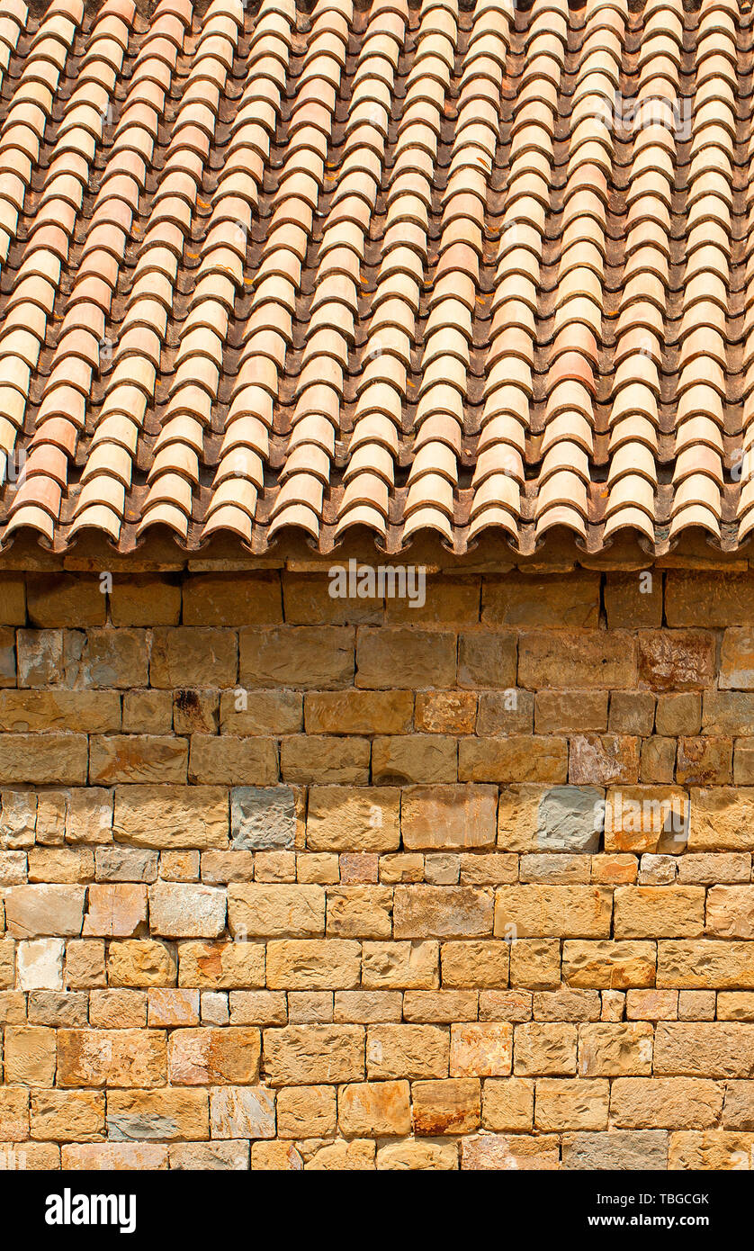 Part of red clay tiled roof and natural stone wall Stock Photo - Alamy