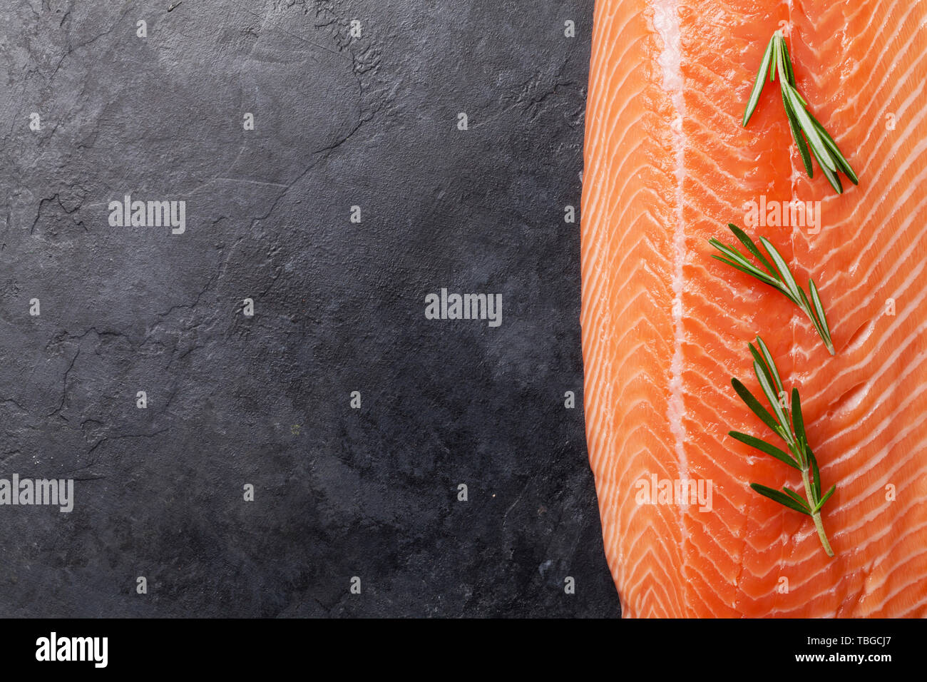 Raw salmon fish fillet with rosemary for cooking on stone table. Top ...