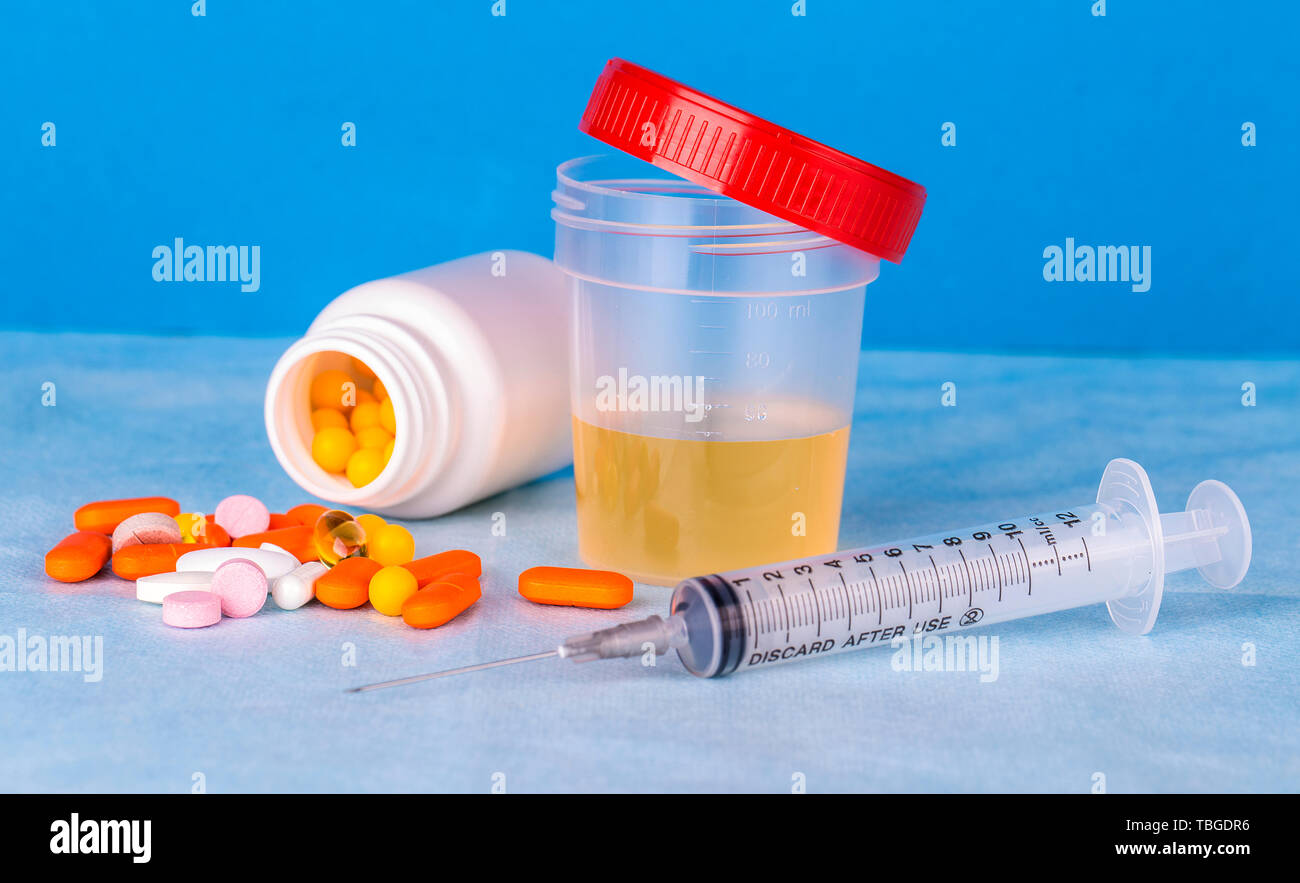 Urine container, syringe and colored pills on blue background Stock ...