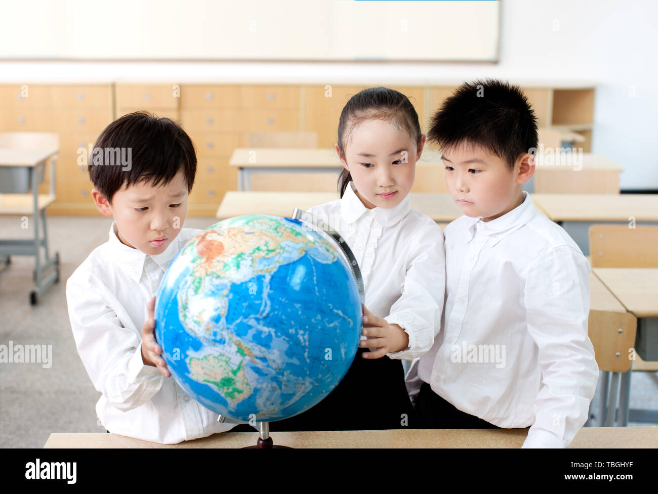 Three primary school students are in class in the classroom Stock Photo ...