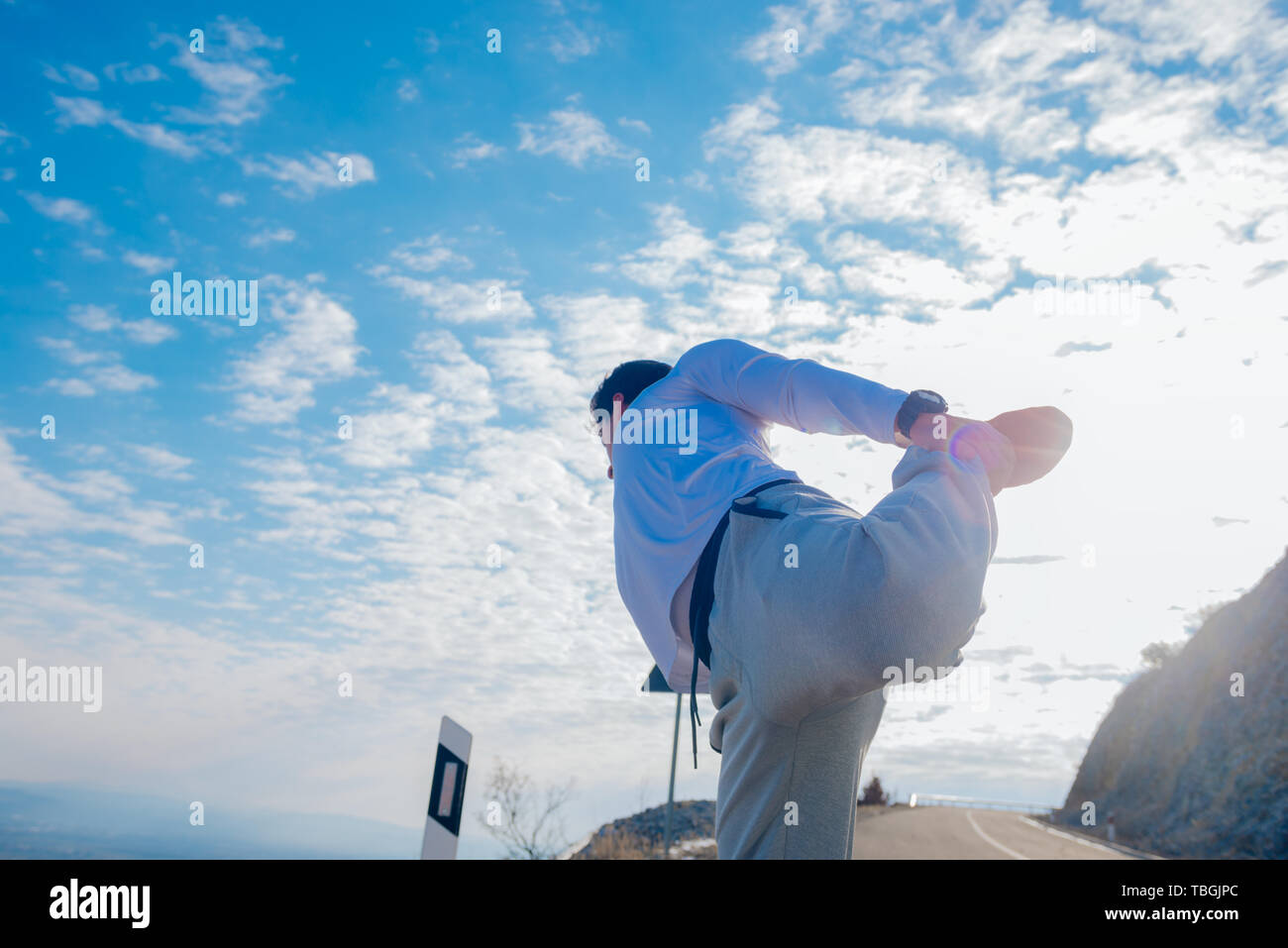 Bodybuilder performing his stretching routine in the morning on an ...
