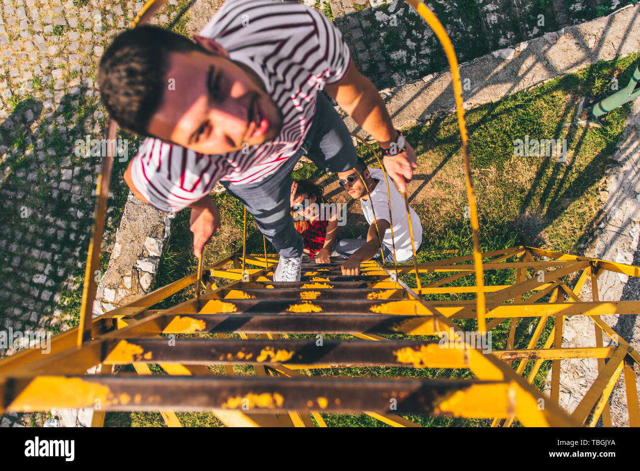 Three friends making jokes and having fun while trying to climb on iron ...